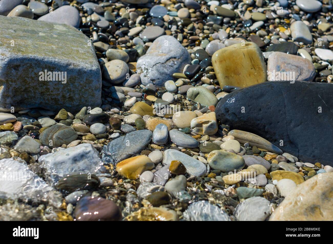 pebble stones on the sea beach, the rolling waves of the sea with foam ...