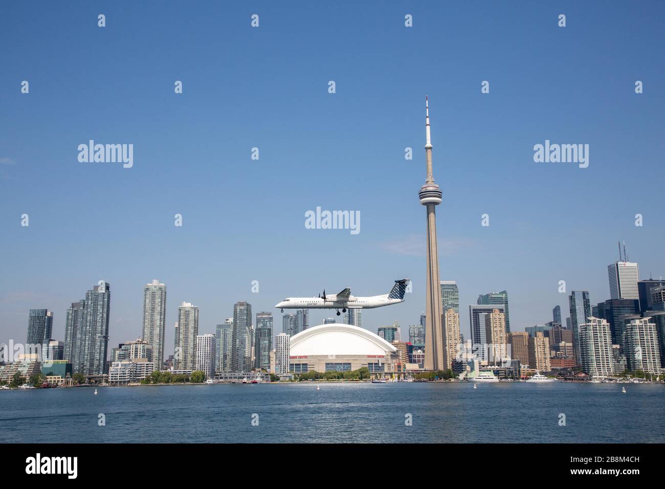 City skyline of Toronto Canada from the shore, with a plane landing at ...