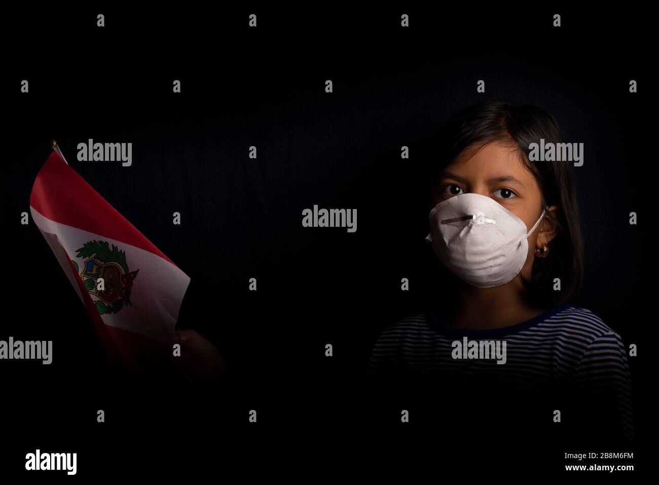 Portrait of little Peruvian girl wearing medical mask and holding ...
