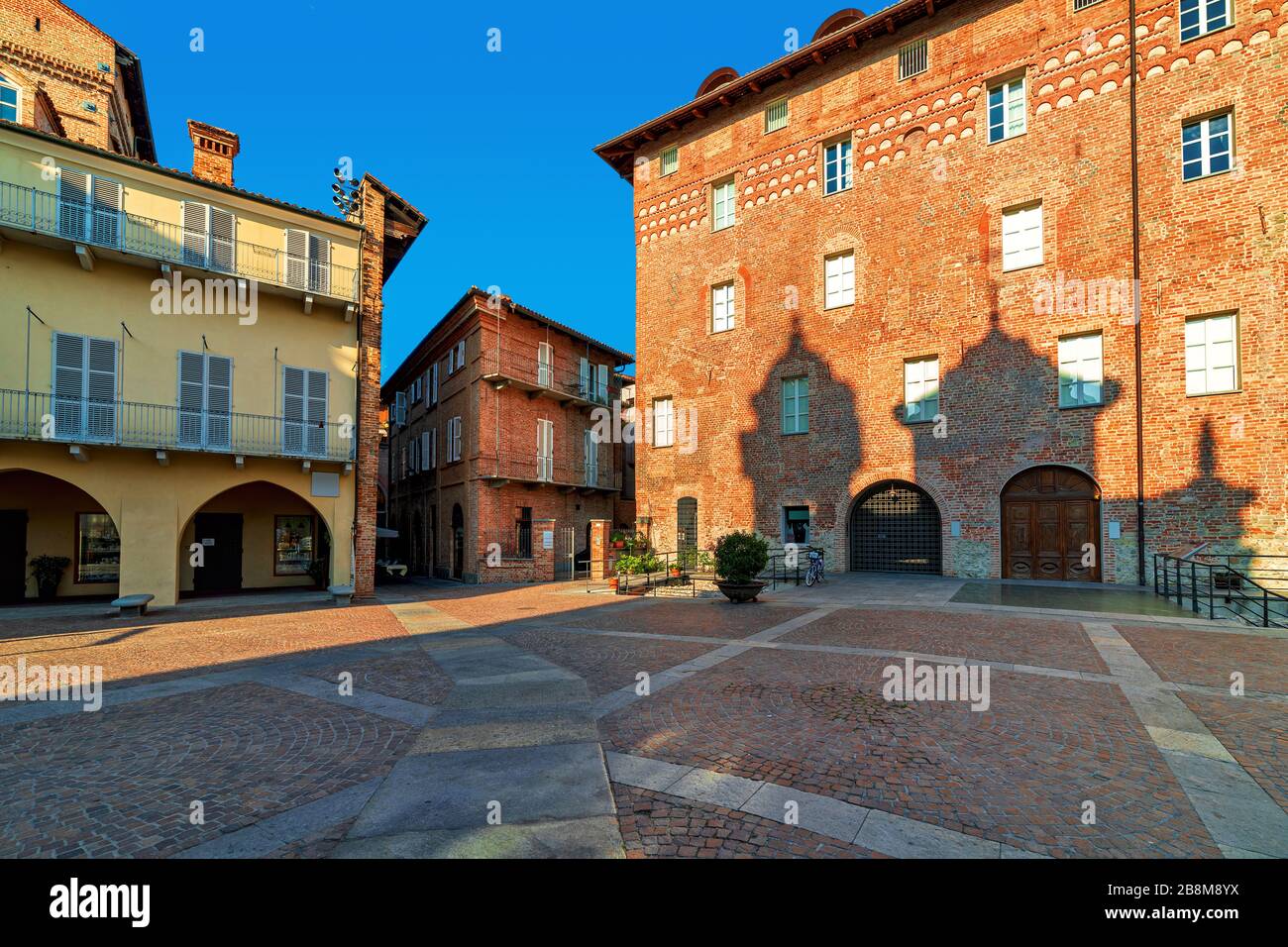 Typical brick buildings on small cobblestone square under blue sky in ...