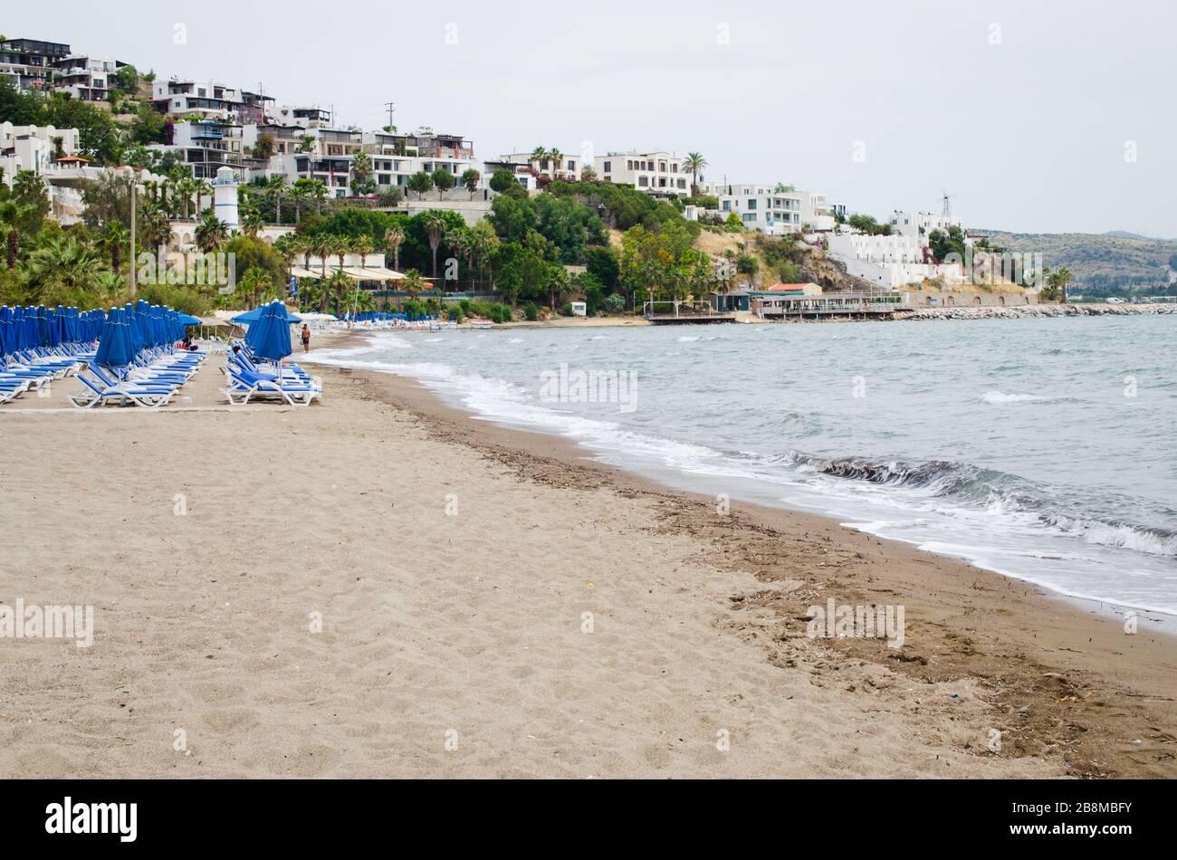Rows of empty blue sun loungers and umbrellas on the beach. Camel Beach ...