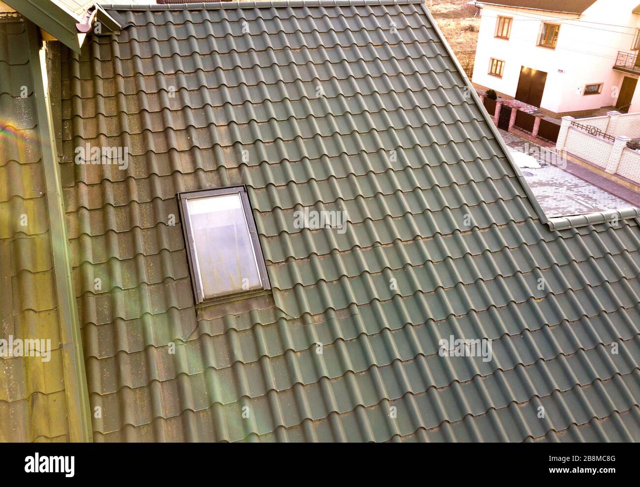 Close-up of new attic plastic window installed in shingled house roof ...