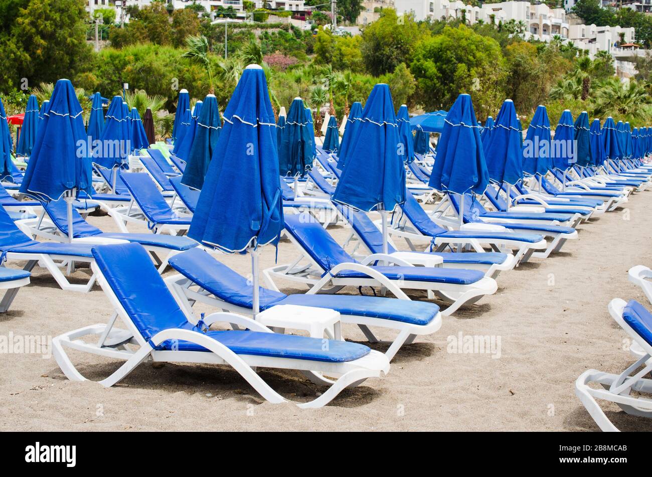 Rows of empty blue sun loungers and umbrellas on the beach. Camel Beach ...
