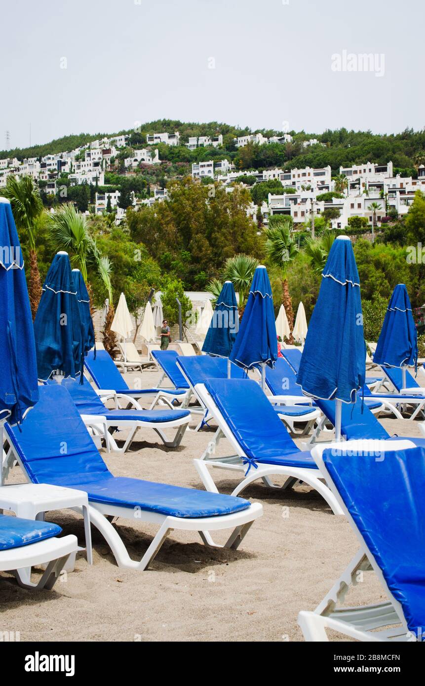 Rows of empty blue sun loungers and umbrellas on the beach. Camel Beach ...