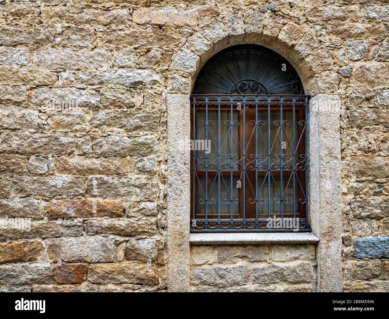 Arched window and ancient wall built with stones of various types and ...