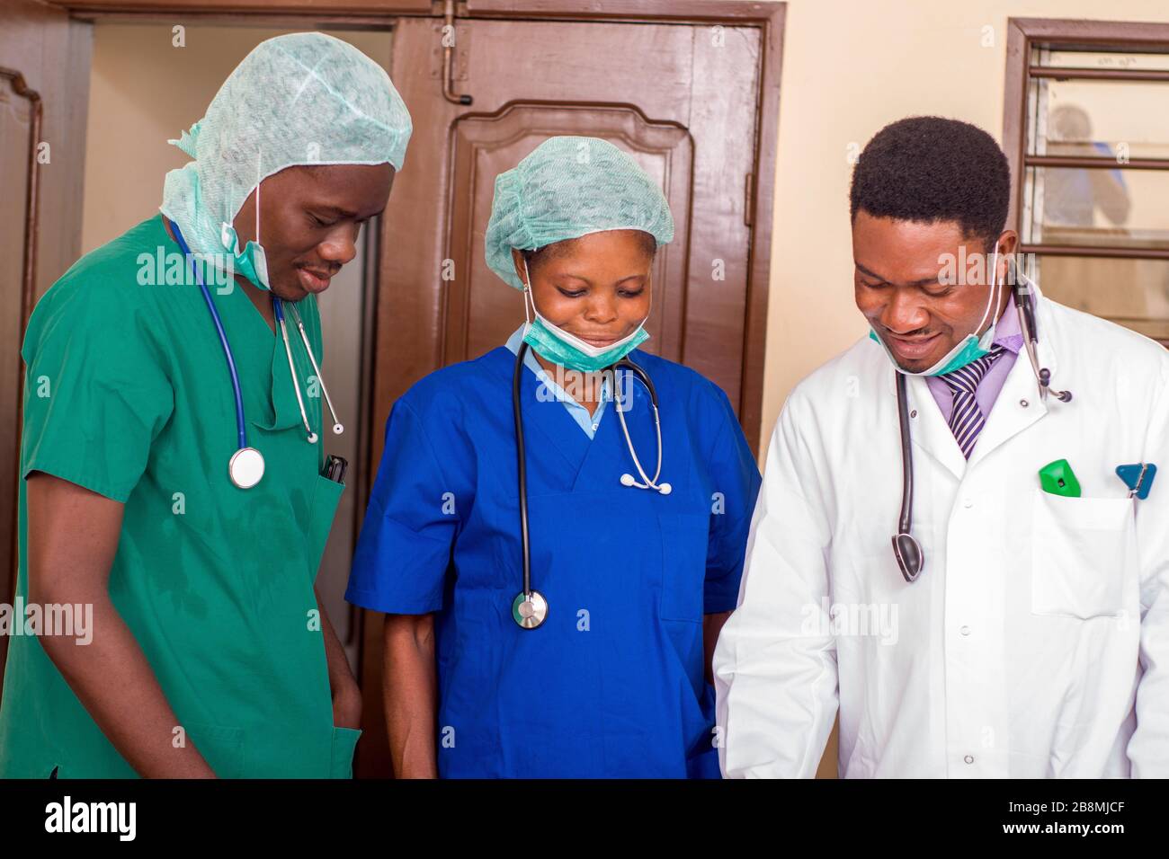 a team of young doctors standing in uniform and watching their program ...