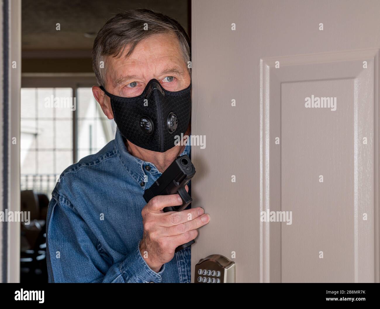 Senior man with face mask looking worried at front door and ready to ...