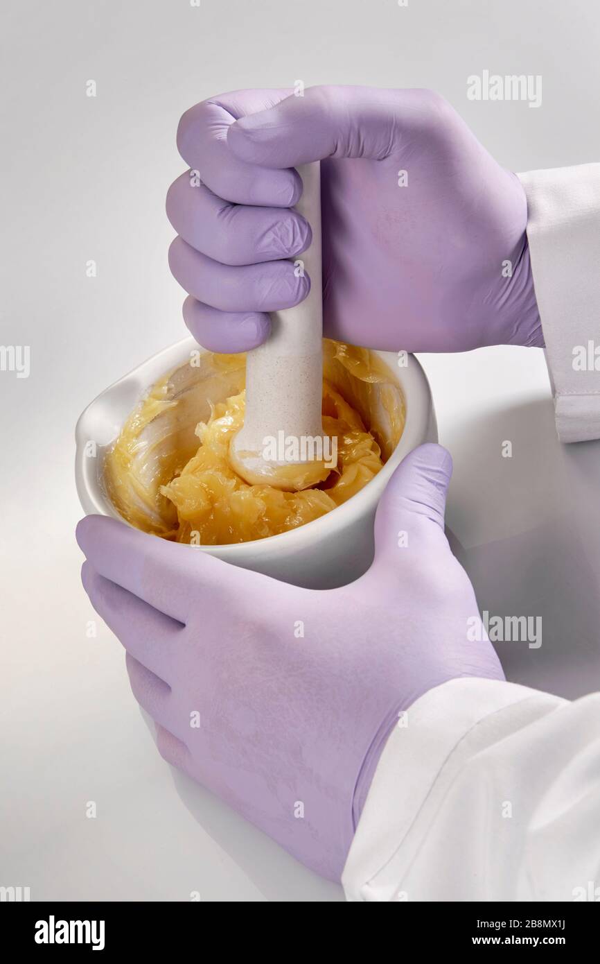 Closeup of the hands of a pharmacist or scientist, holding a mortar and ...