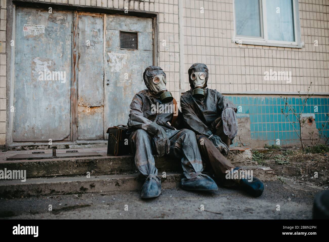 Couple in love sits in NBC protective suits and gas masks near building ...