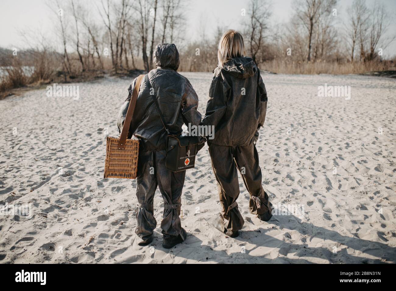 Couple in love walks at beach in NBC protective suits. Concept of a ...