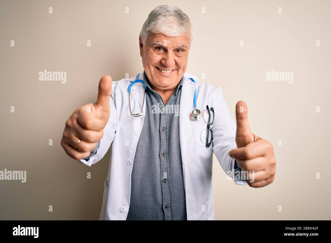 Senior handsome hoary doctor man wearing coat and stethoscope over ...