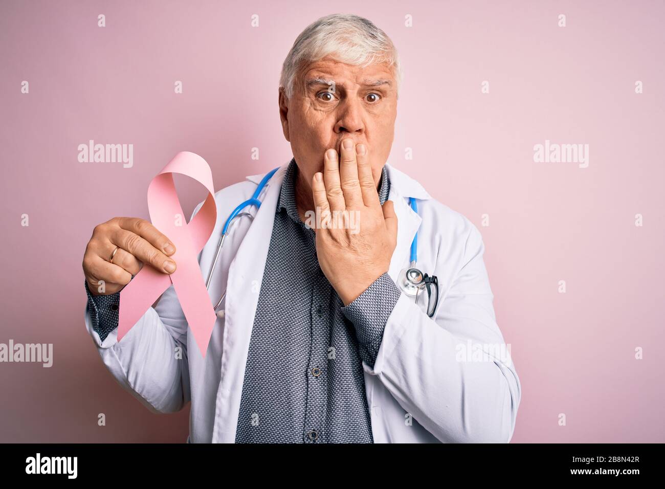 Senior handsome hoary doctor man wearing stethoscope holding pink ...
