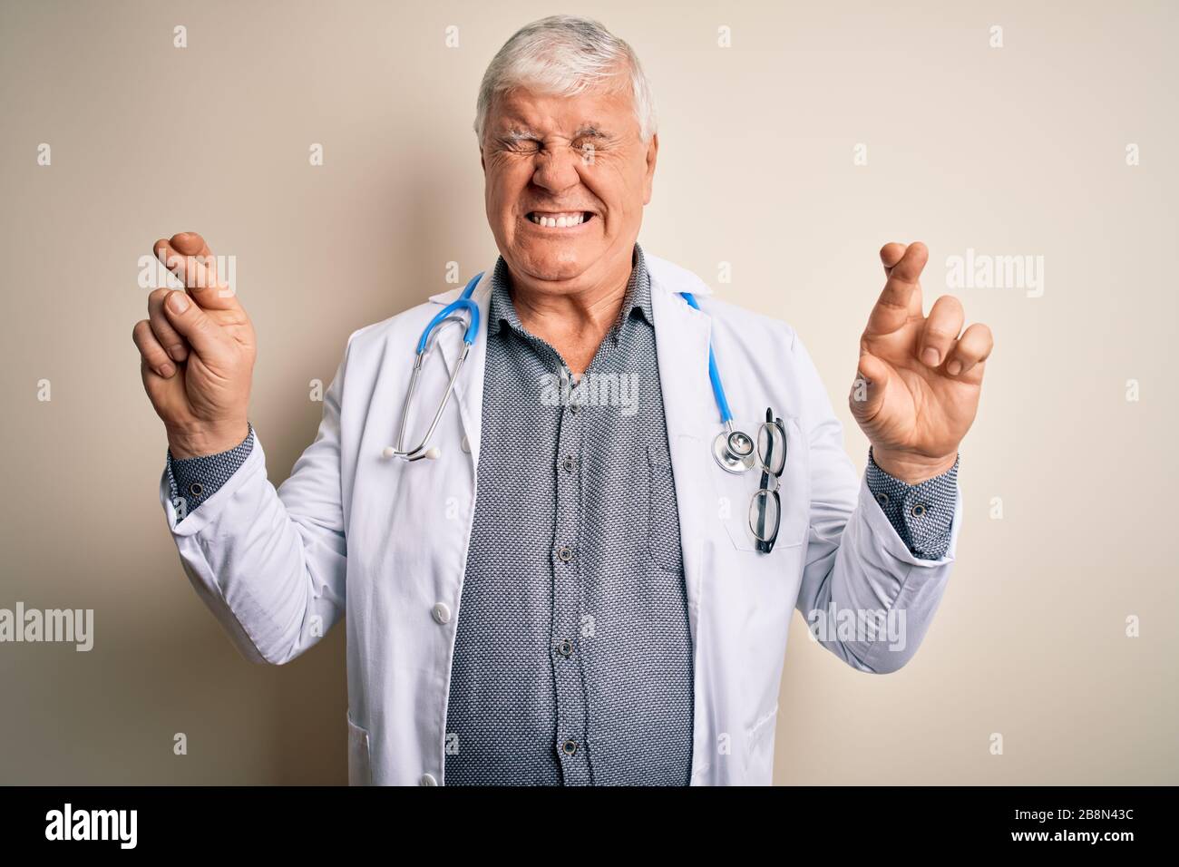 Senior handsome hoary doctor man wearing coat and stethoscope over ...