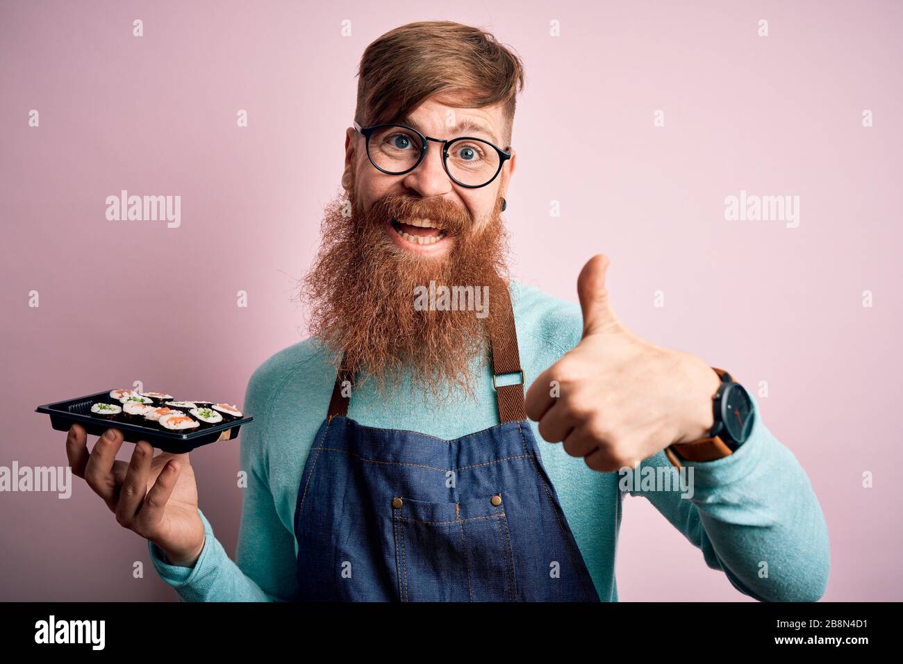 Redhead Irish cook man with beard holding maki sushi tray over isolated ...