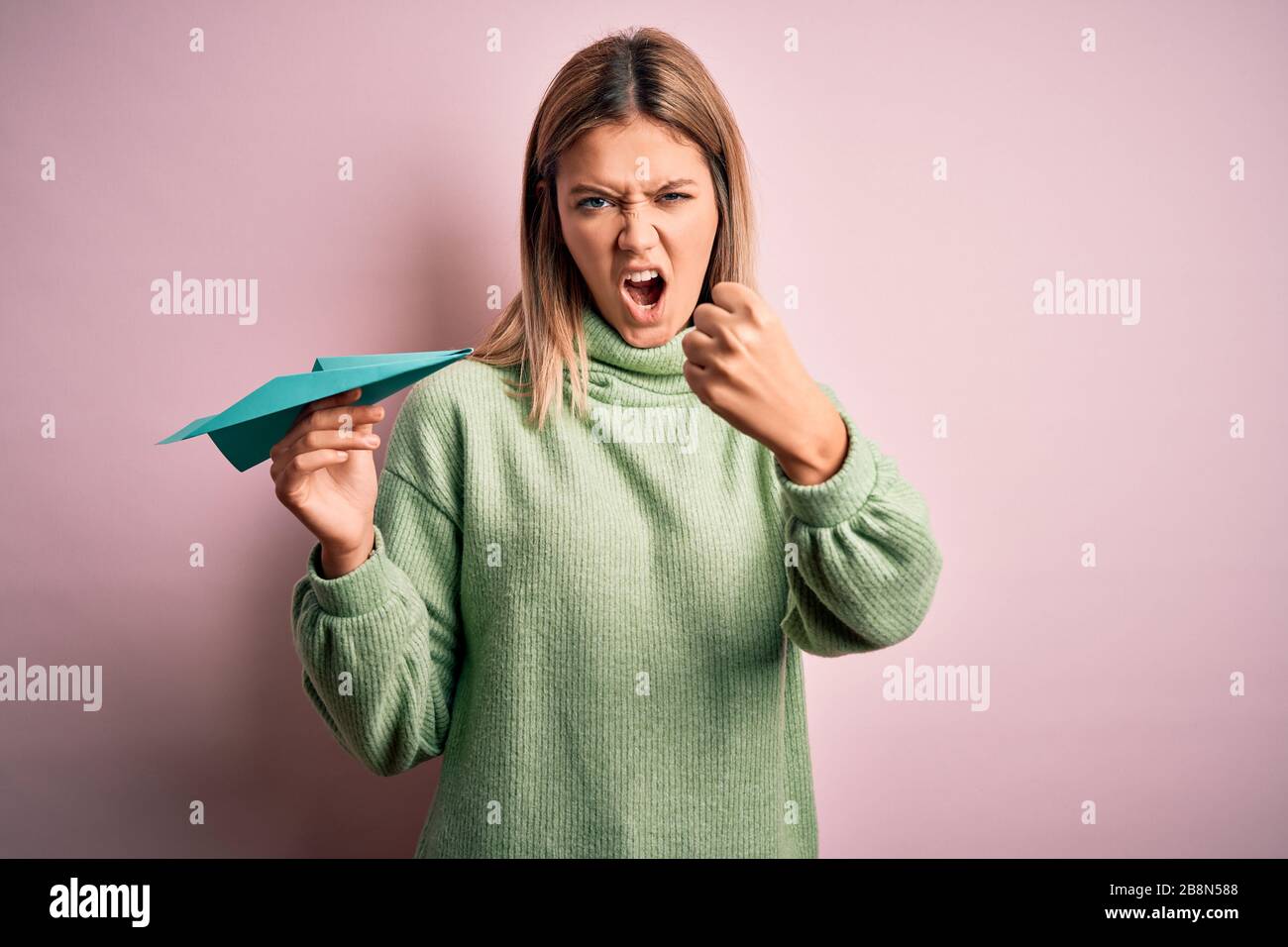 Young beautiful woman holding paper airplane standing over isolated ...