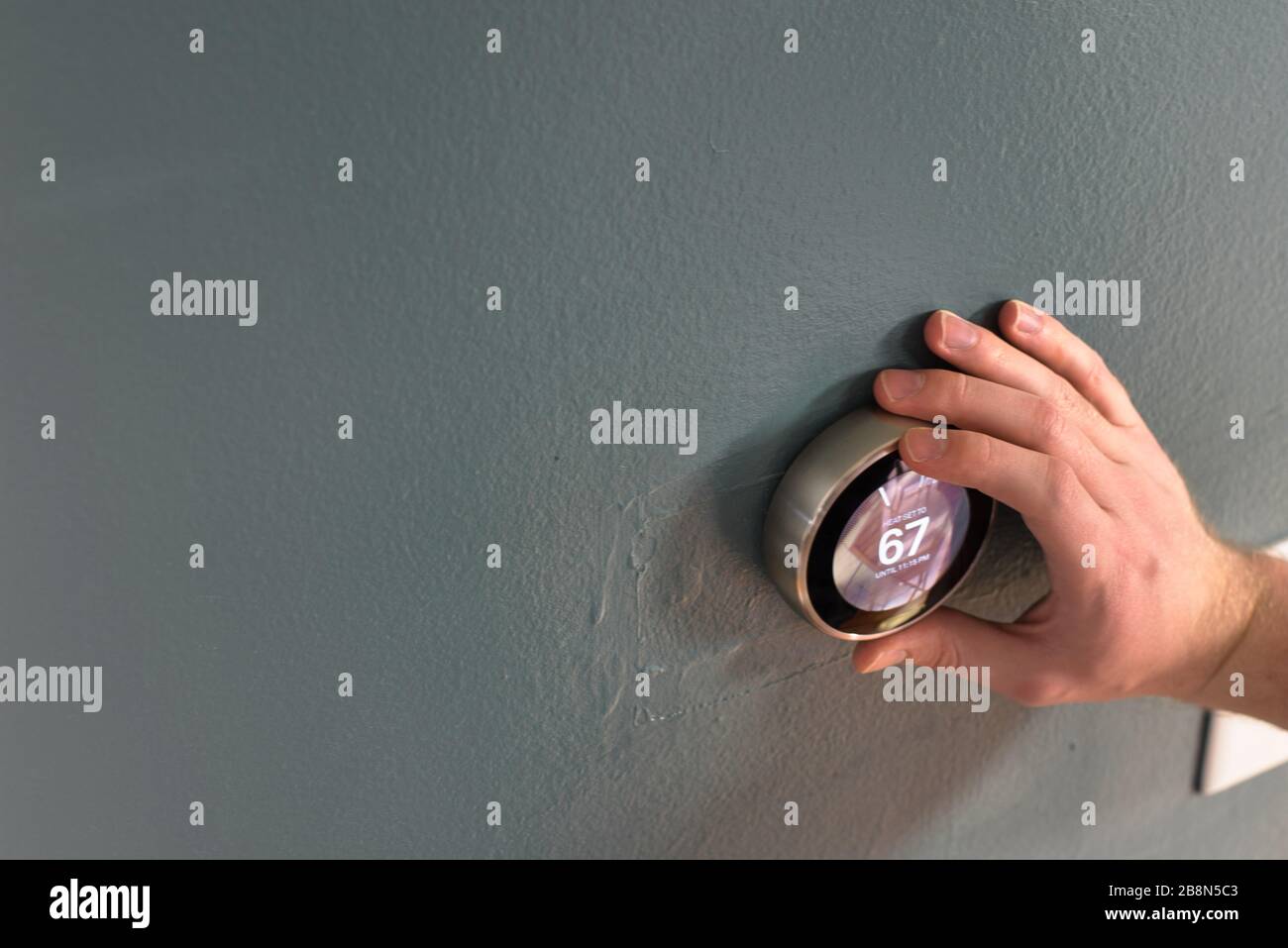 Hand adjusting the dial on smart home thermostat. Pressing center ...