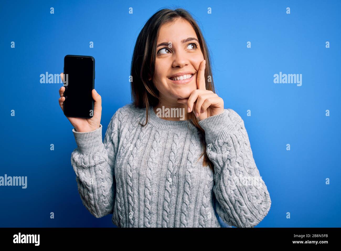 Young woman showing blank smartphone screen over blue isolated ...