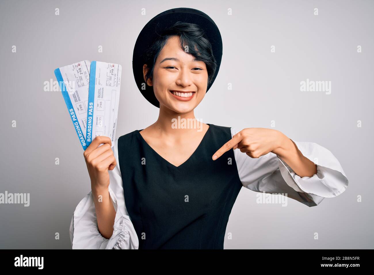 Young beautiful chinese tourist woman holding boarding pass airlane ...