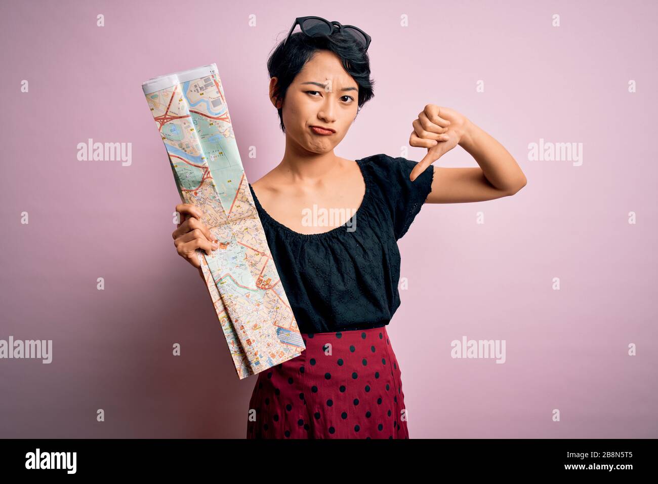 Young beautiful asian tourist girl on vacation holding city map over ...