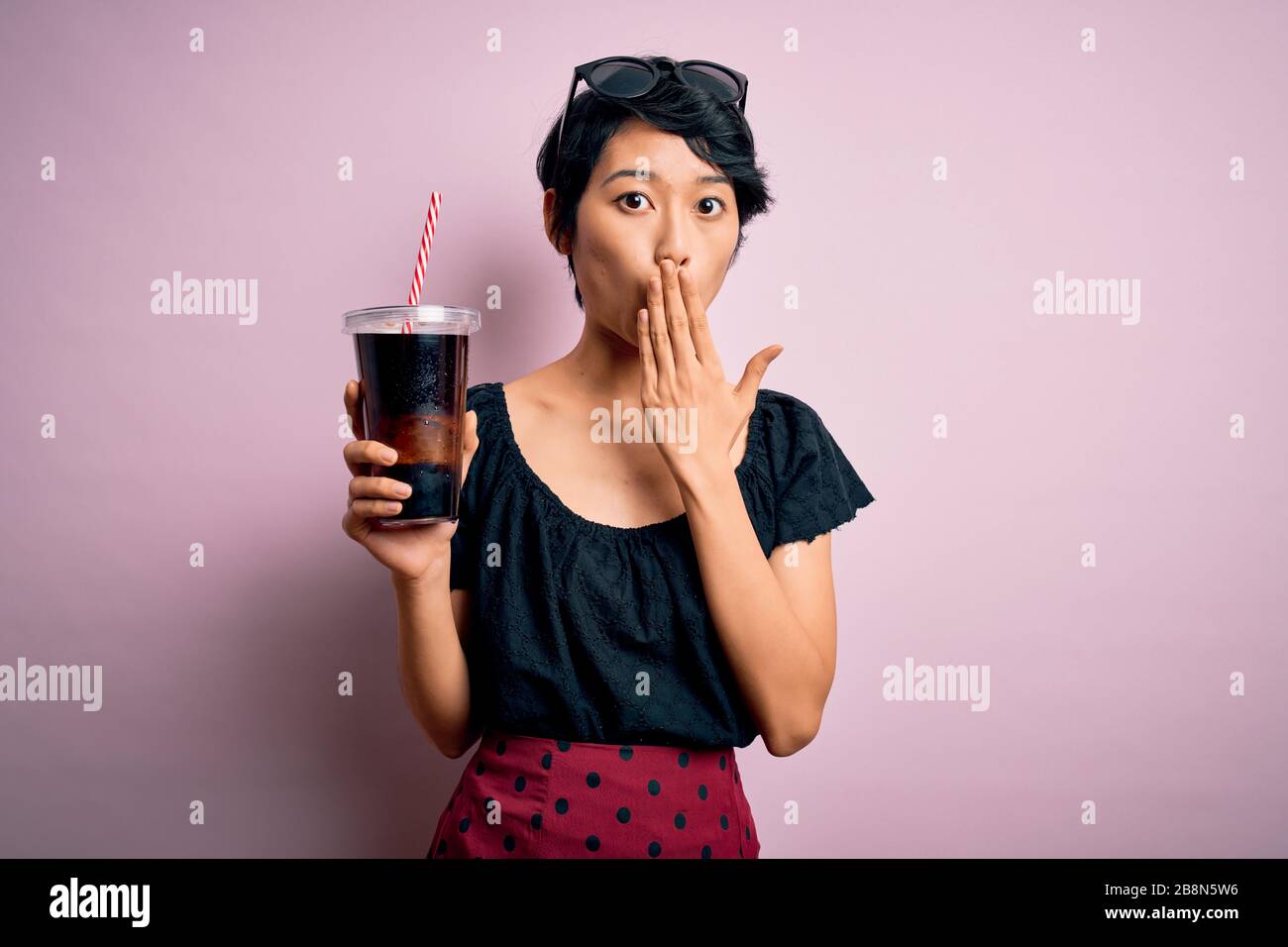 Young beautiful chinese woman drinking cola fizzy beverage using straw ...