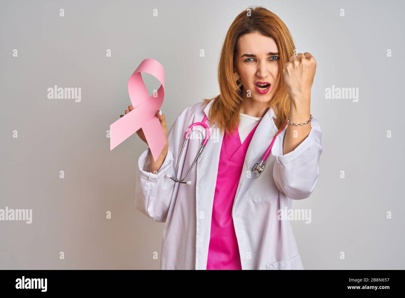 Redhead caucasian doctor woman holding pink cancer ribbon over isolated ...