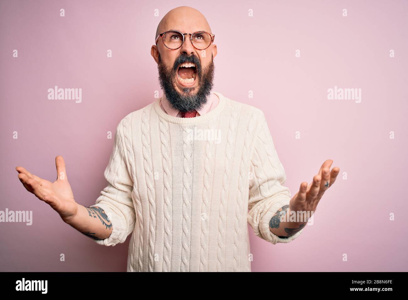 Handsome bald man with beard and tattoo wearing glasses and sweater ...