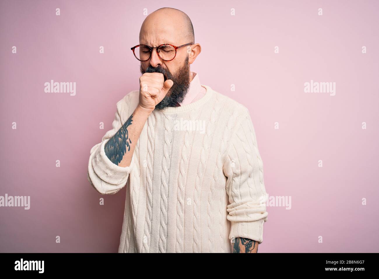 Handsome bald man with beard and tattoo wearing glasses and sweater ...