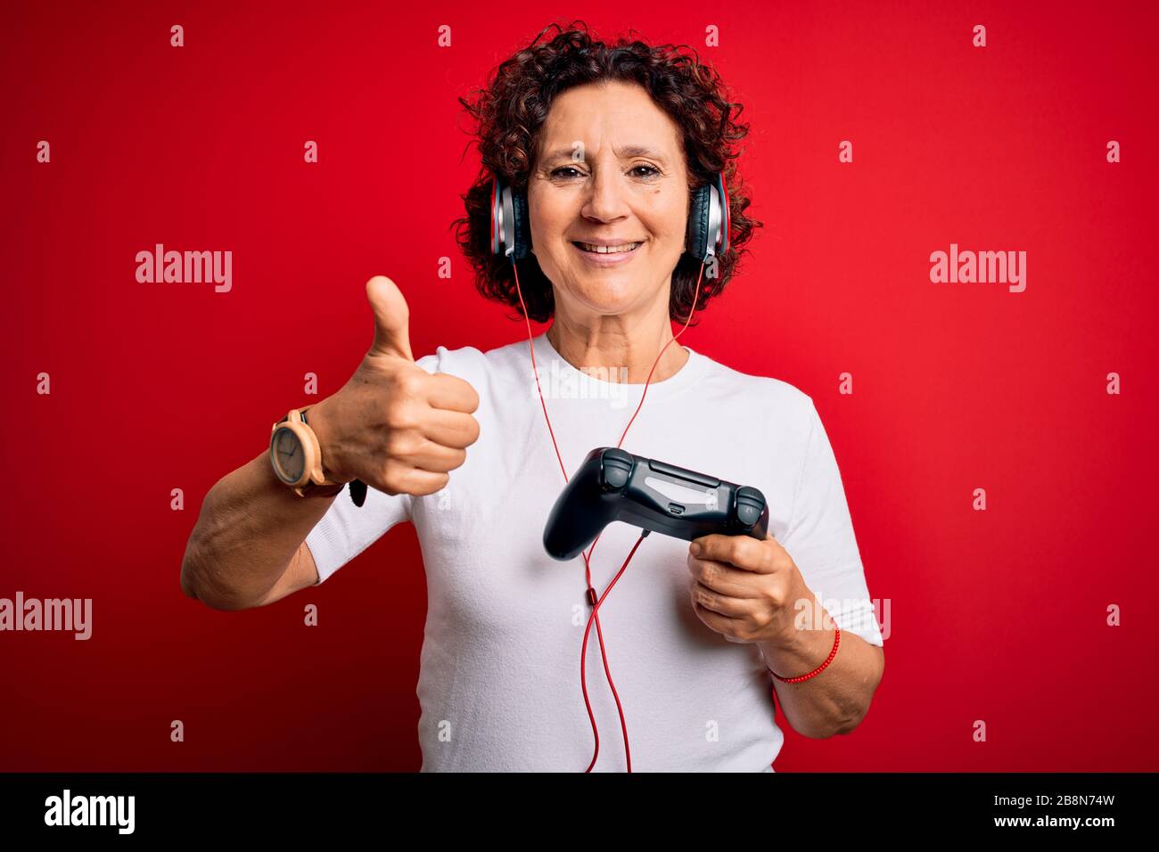 Middle age curly hair gamer woman playing video game using joystick and ...