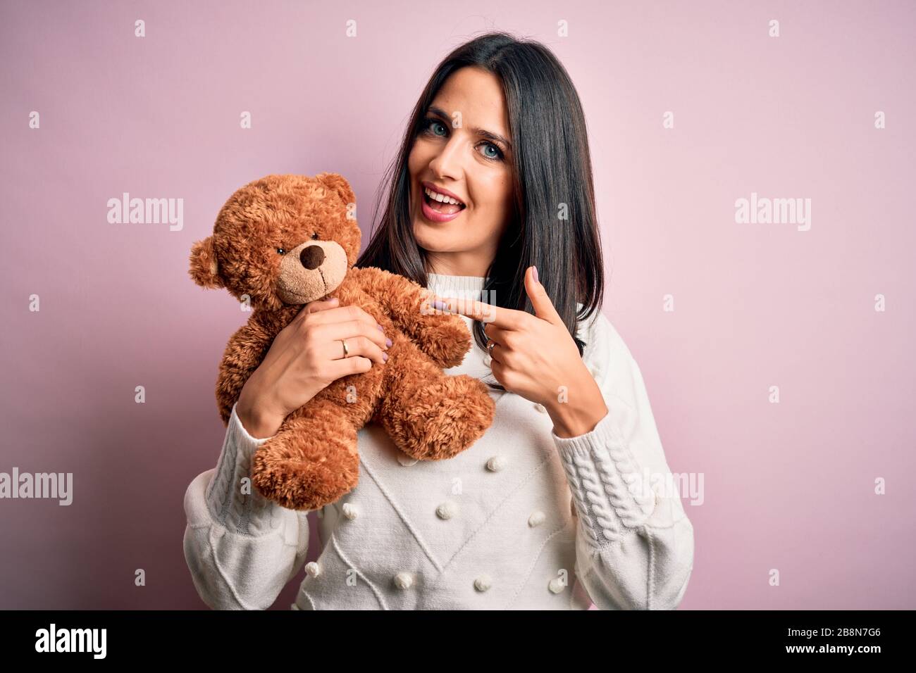 Young brunette woman with blue eyes hugging teddy bear stuffed animal ...