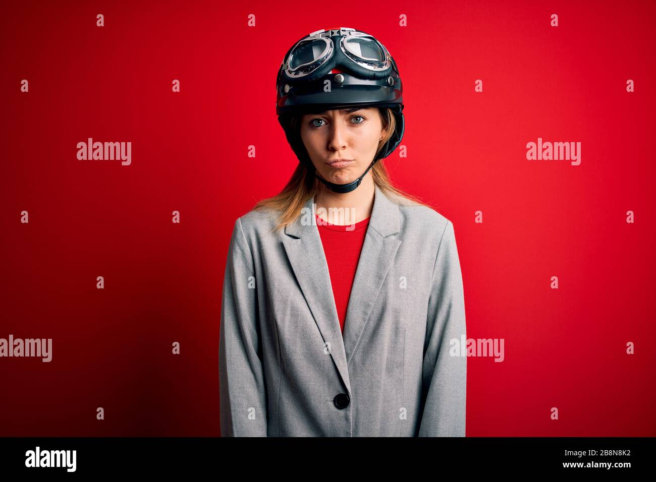 Young beautiful blonde motorcyclist woman wearing motorcycle helmet ...