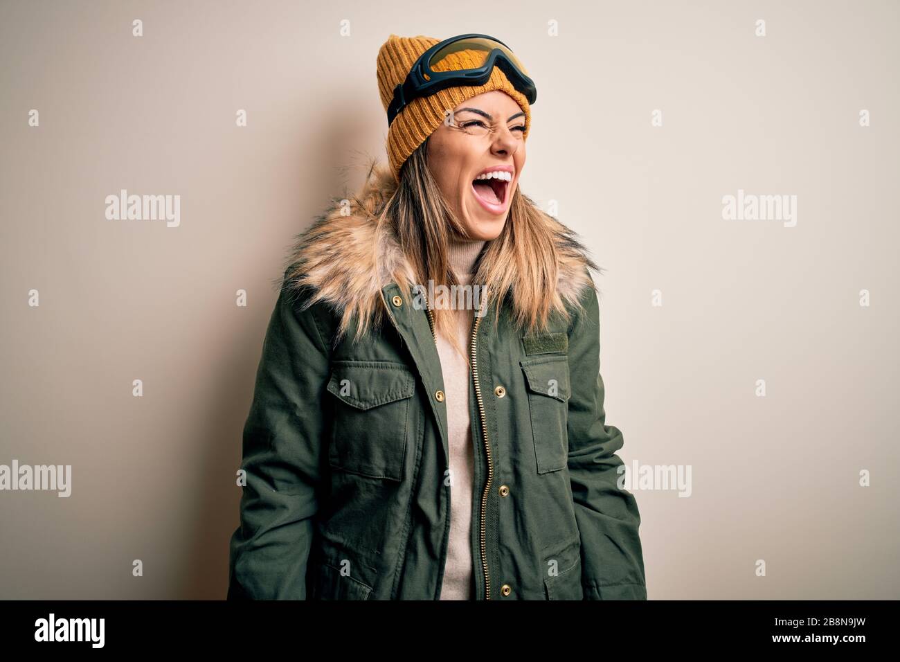 Young brunette skier woman wearing snow clothes and ski goggles over ...