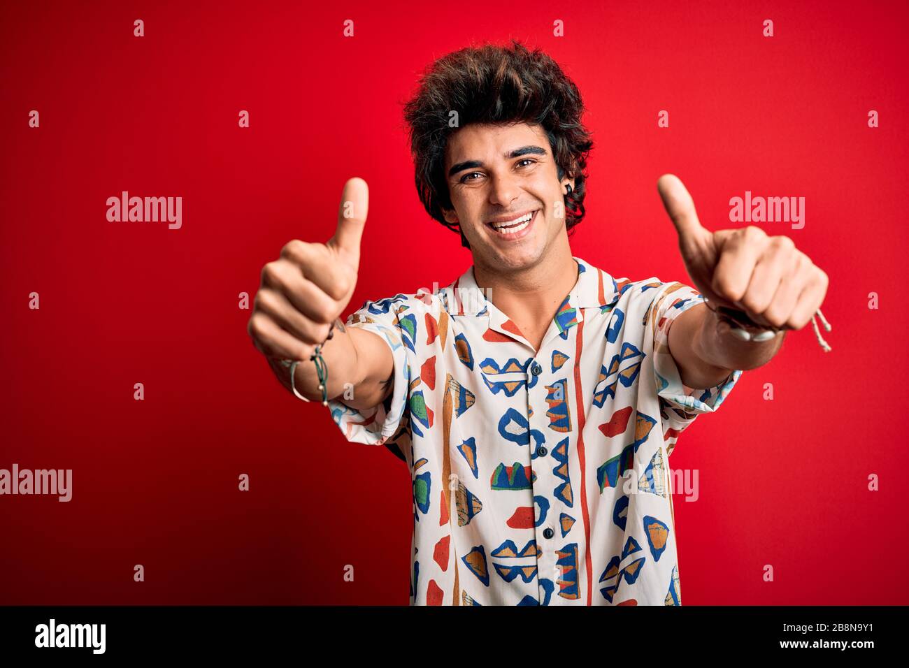 Young handsome man on vacation wearing summer shirt over isolated red ...