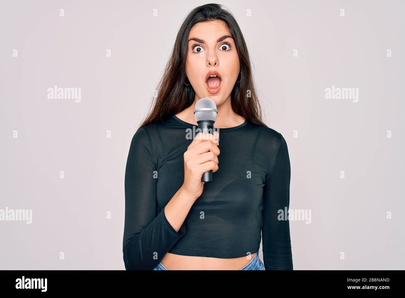 Young beautiful singer performer girl singing using music microphone ...