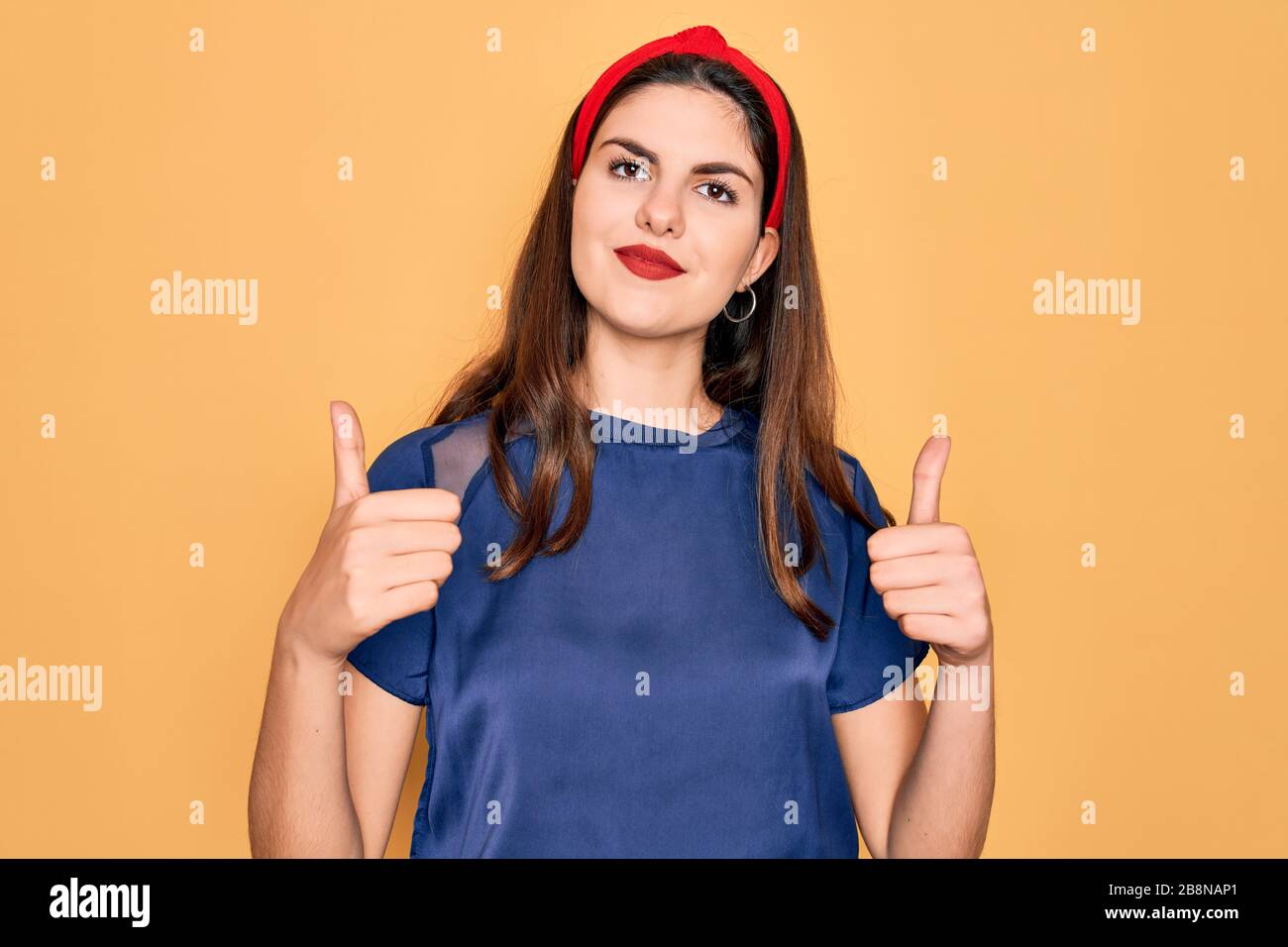 Young beautiful brunette woman wearing red lips over yellow background ...