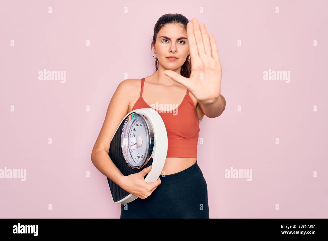 Young beautiful fitness woman wearing sport clothes holding weighting ...