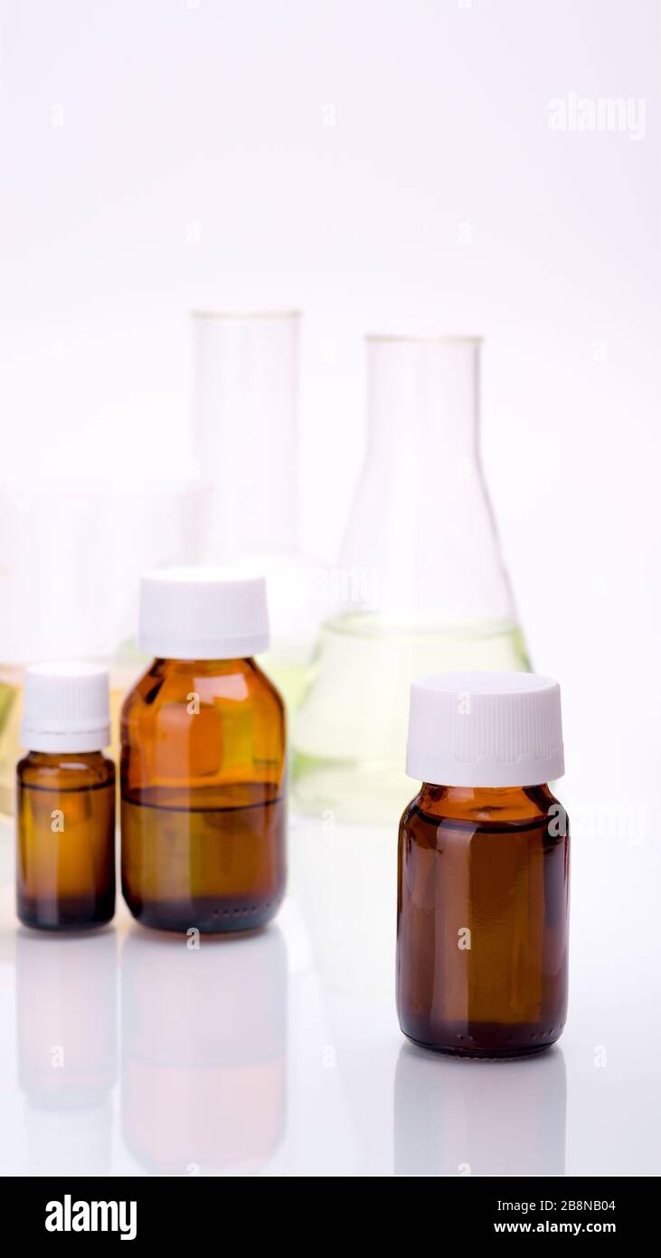 Medicine bottle and laboratory flasks against white background ...