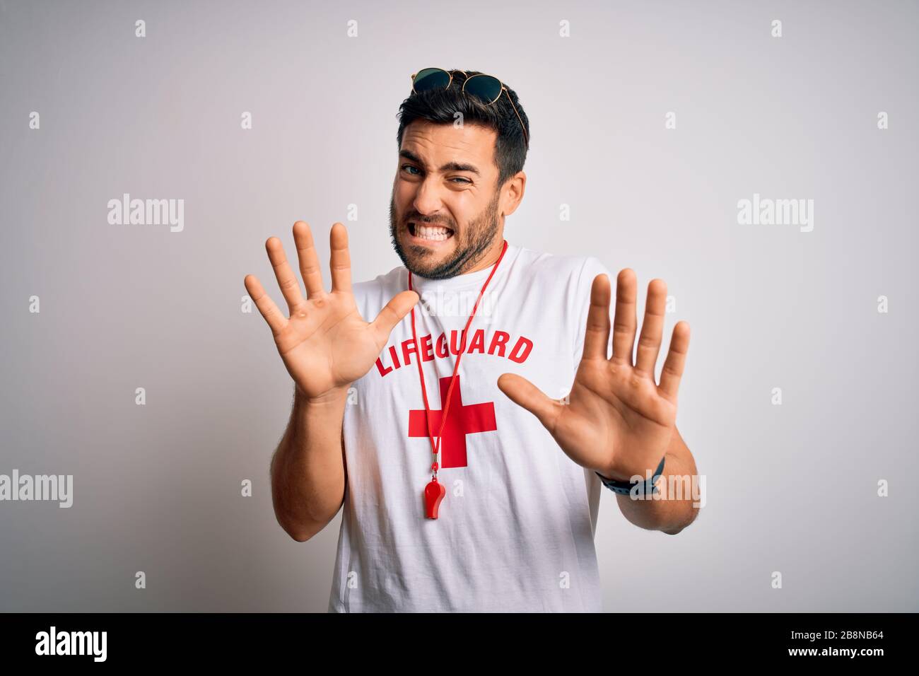 Young handsome lifeguard man with beard wearing t-shirt with red cross ...