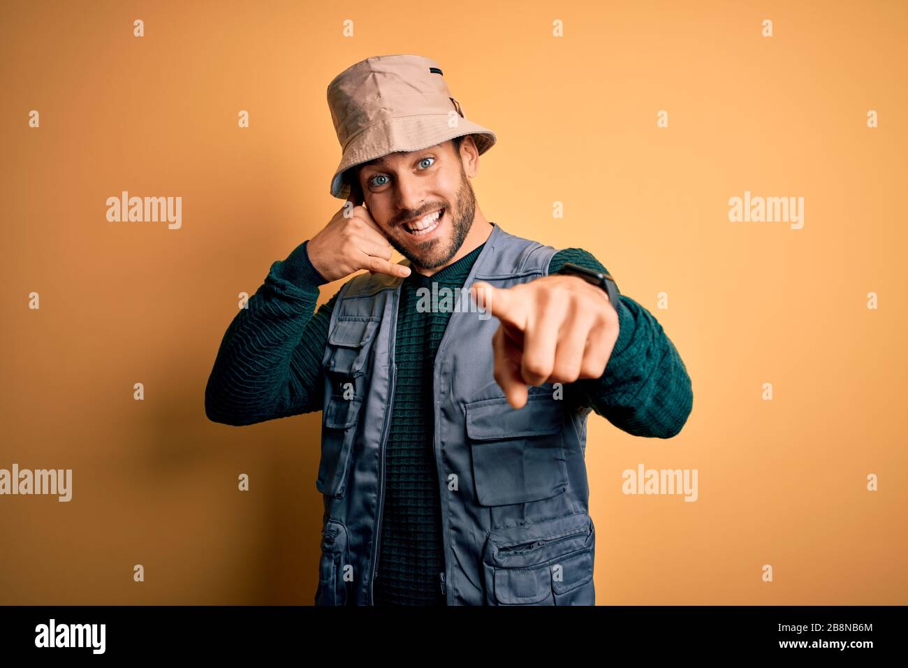 Handsome tourist man with beard on vacation wearing explorer hat over ...