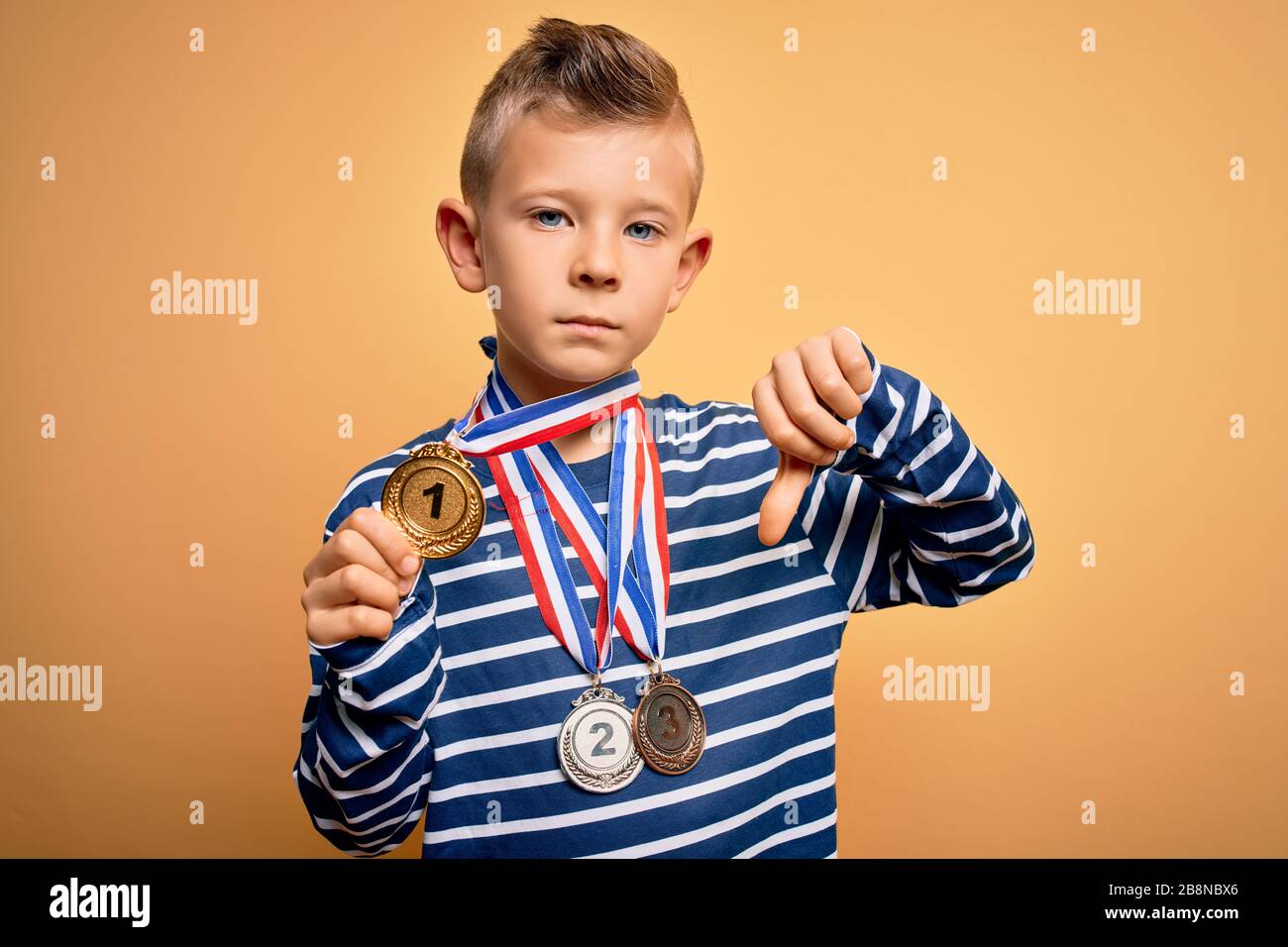 Young little caucasian winner kid wearing award competition medals over ...