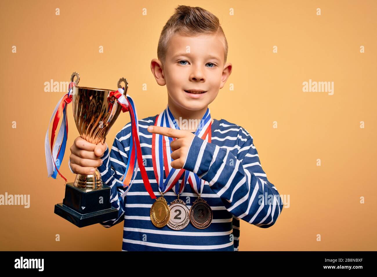 Young little caucasian kid wearing winner medals and victory award ...
