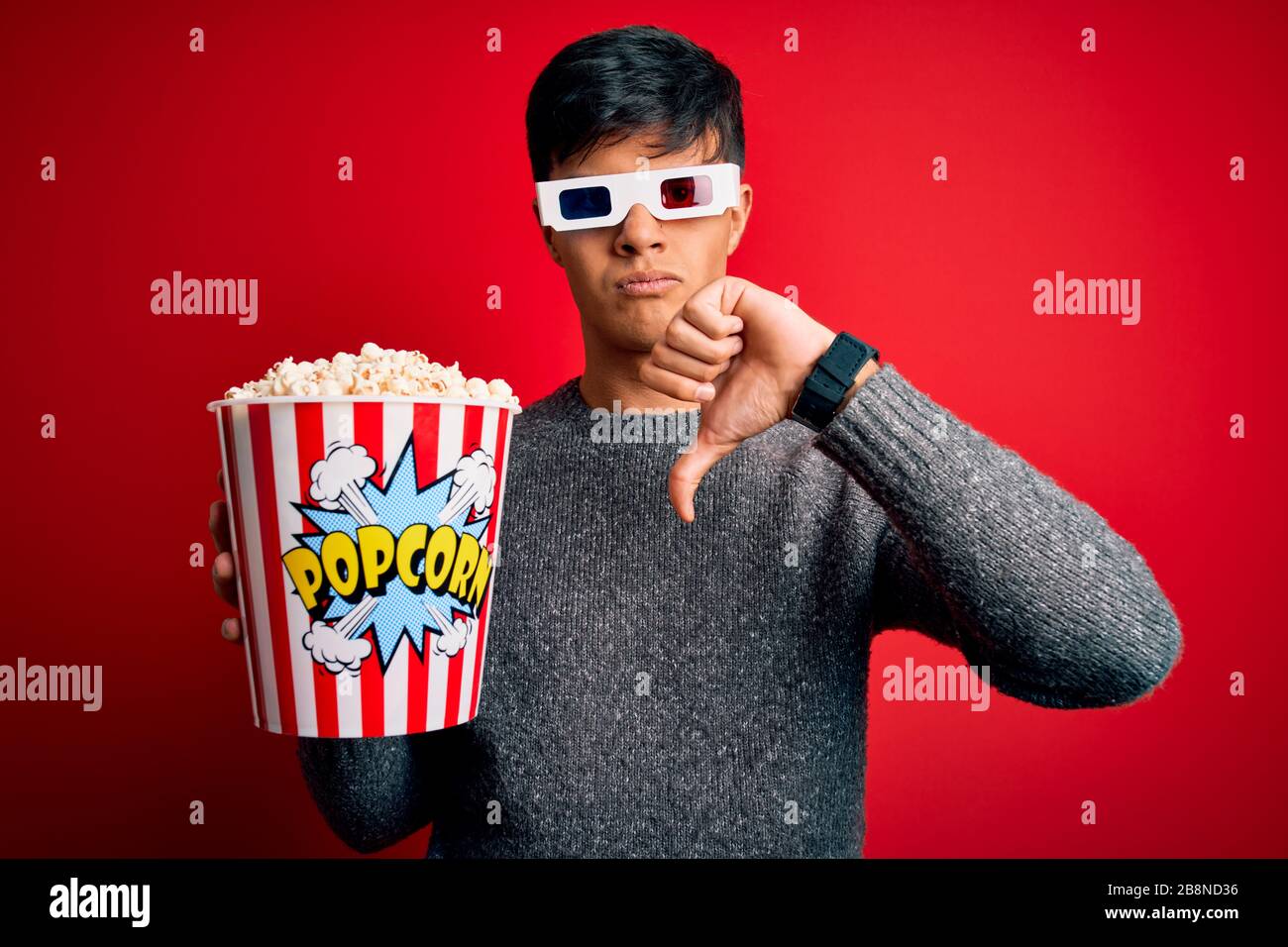 Young handsome man watching movie eating popcorns snack over isolated ...