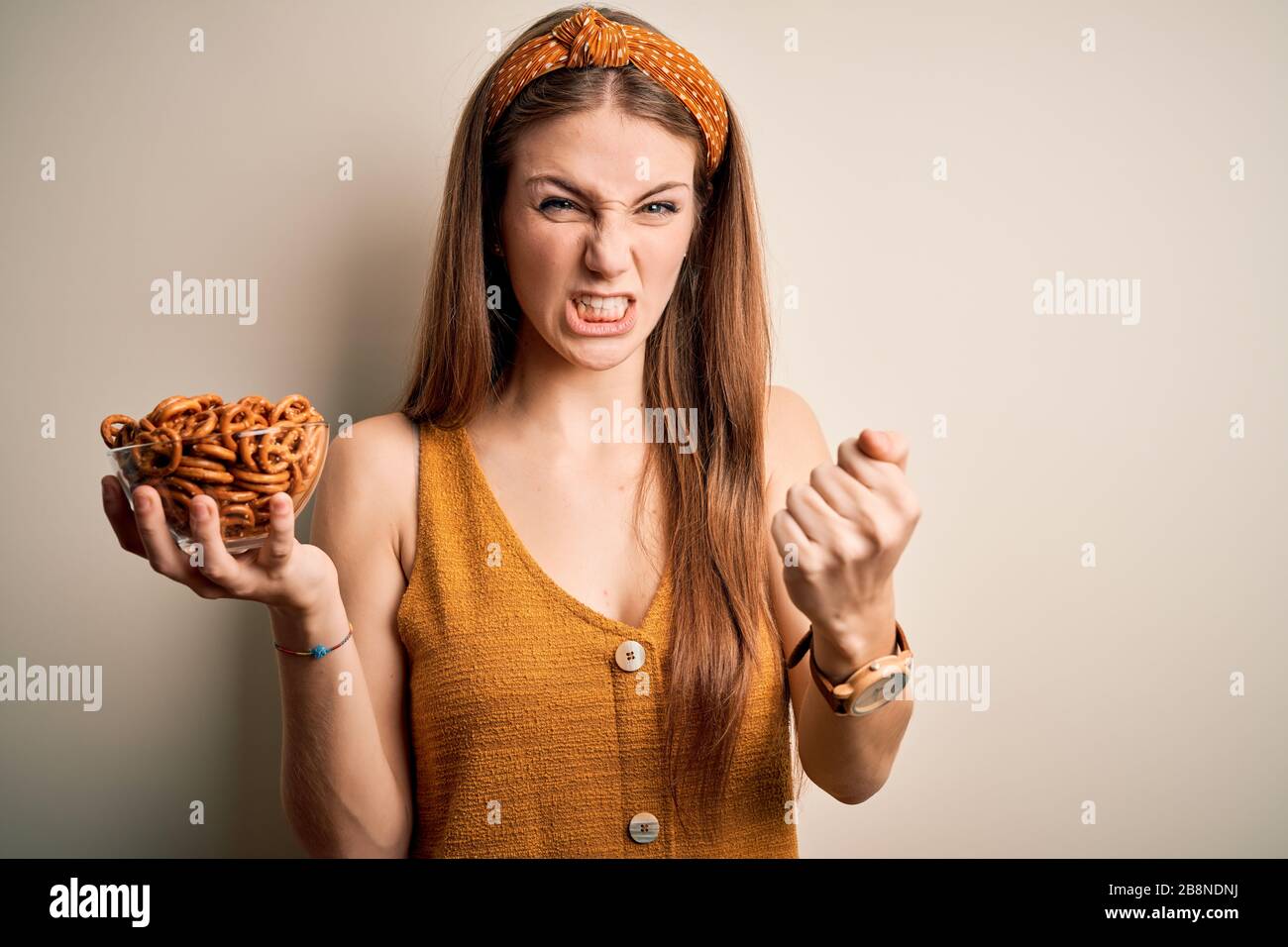 Young beautiful redhead woman holding bowl with german baked pretzels ...