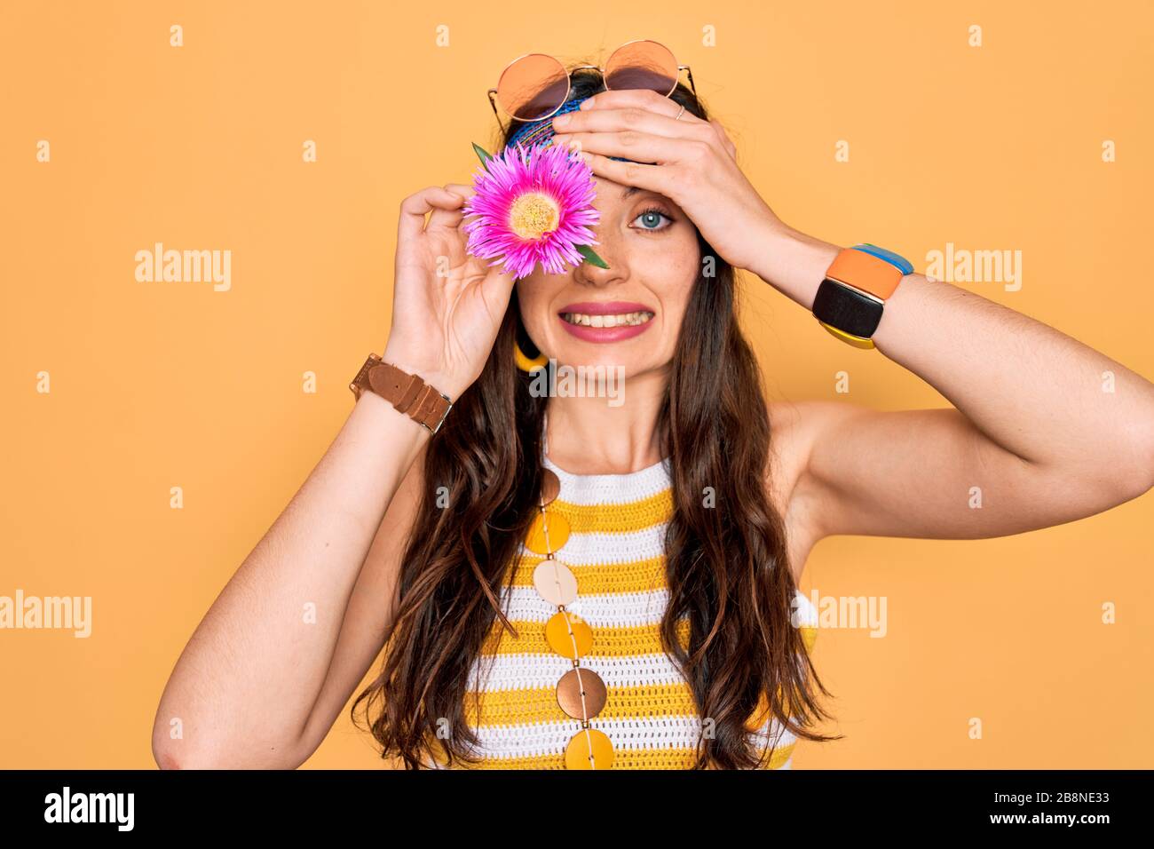 Young beautiful hippie woman with blue eyes wearing sunnglasses holding ...