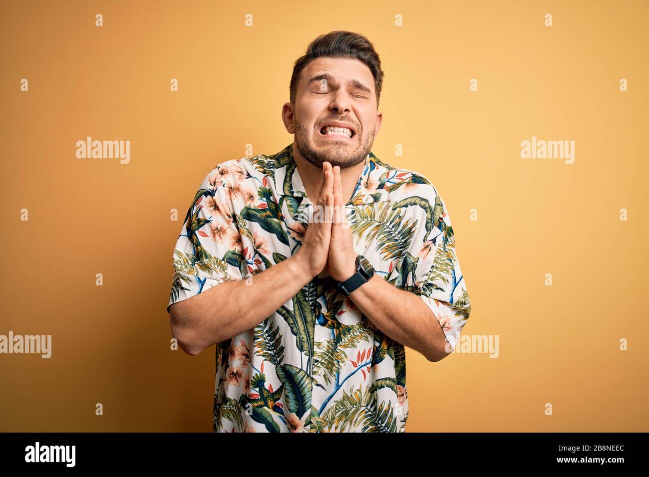 Young man with blue eyes on vacation wearing floral summer shirt over ...