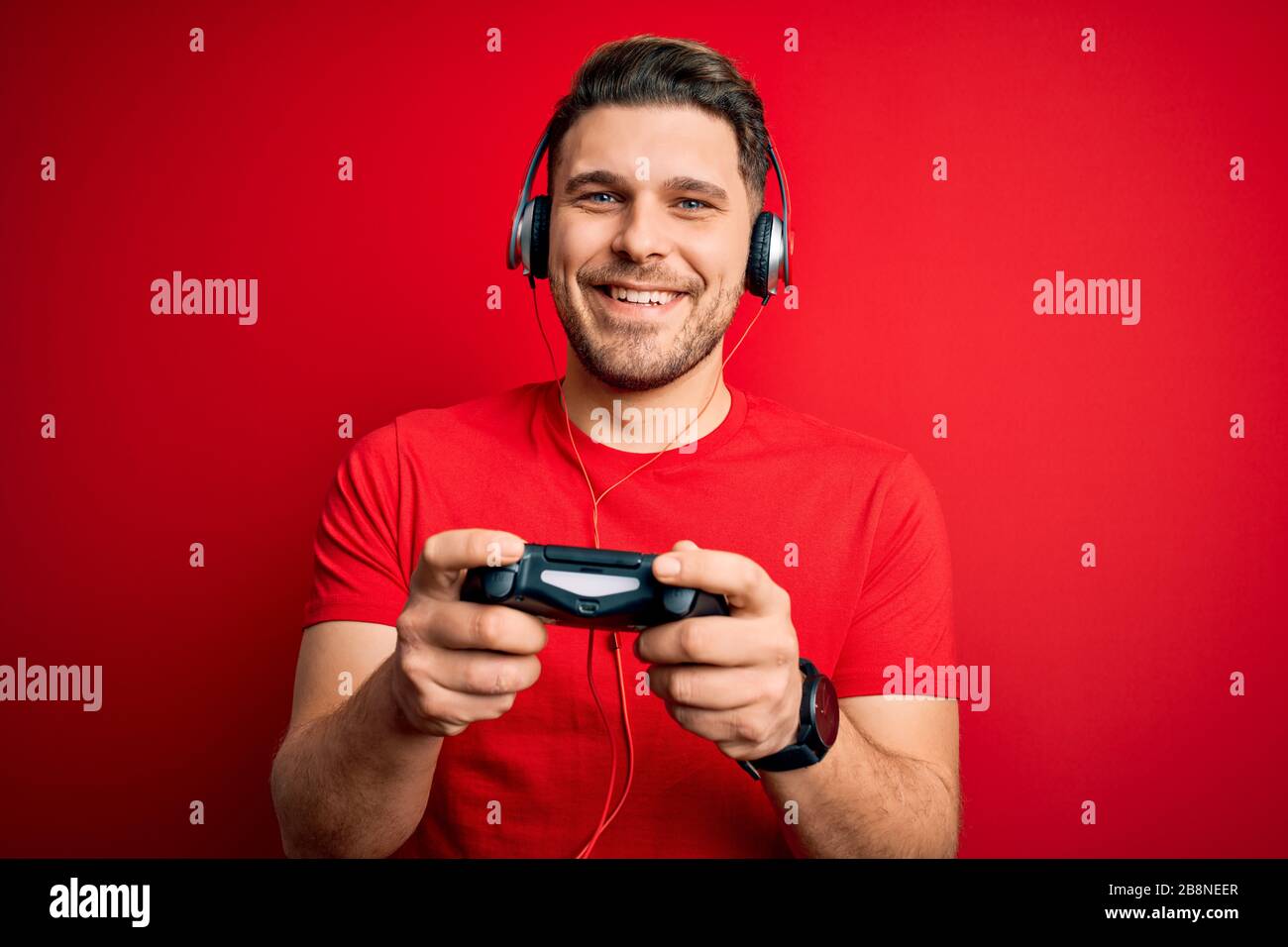 Young gamer man with blue eyes playing video games using gamepad ...