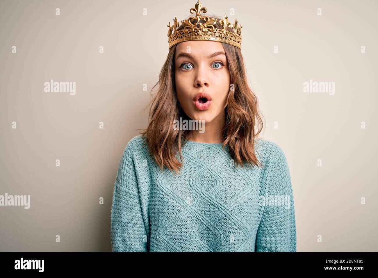 Young blonde girl wearing queen golden crown over isolated background ...