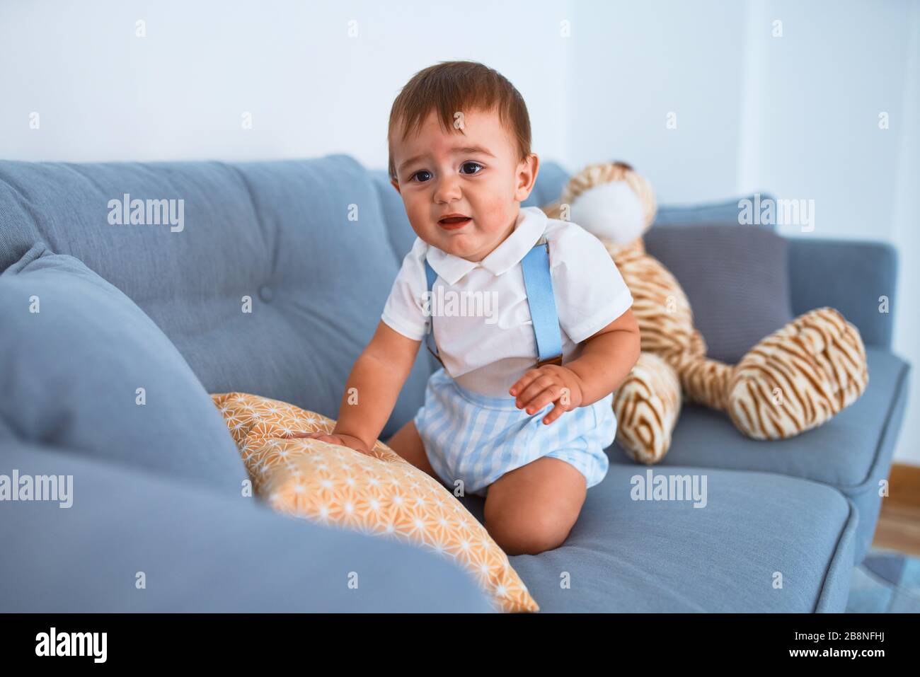 Adorable toddler sitting on the sofa crying at home Stock Photo - Alamy