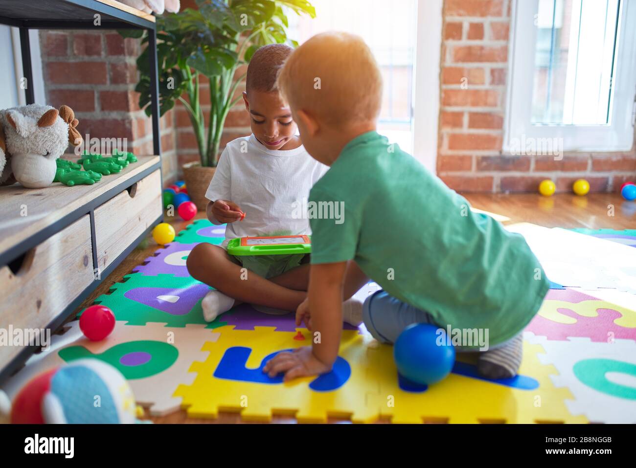 Adorable toddlers playing around lots of toys at kindergarten Stock ...
