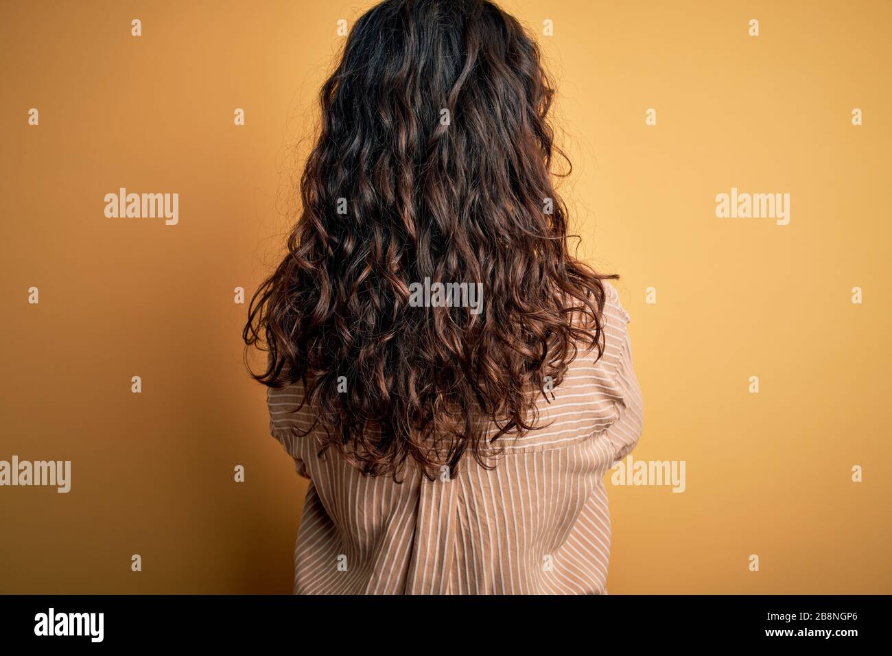 Beautiful woman with curly hair wearing striped shirt and glasses over ...