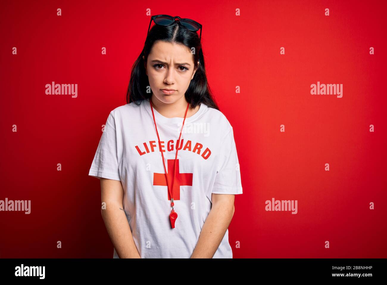 Young lifeguard woman wearing secury guard equipent over red background ...